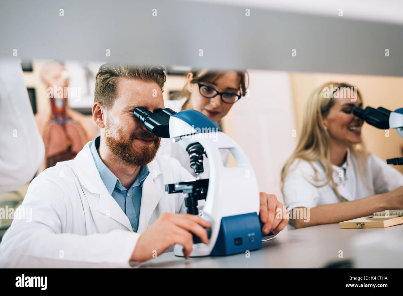 Group of scientists doing research looking through microscope Stock ...