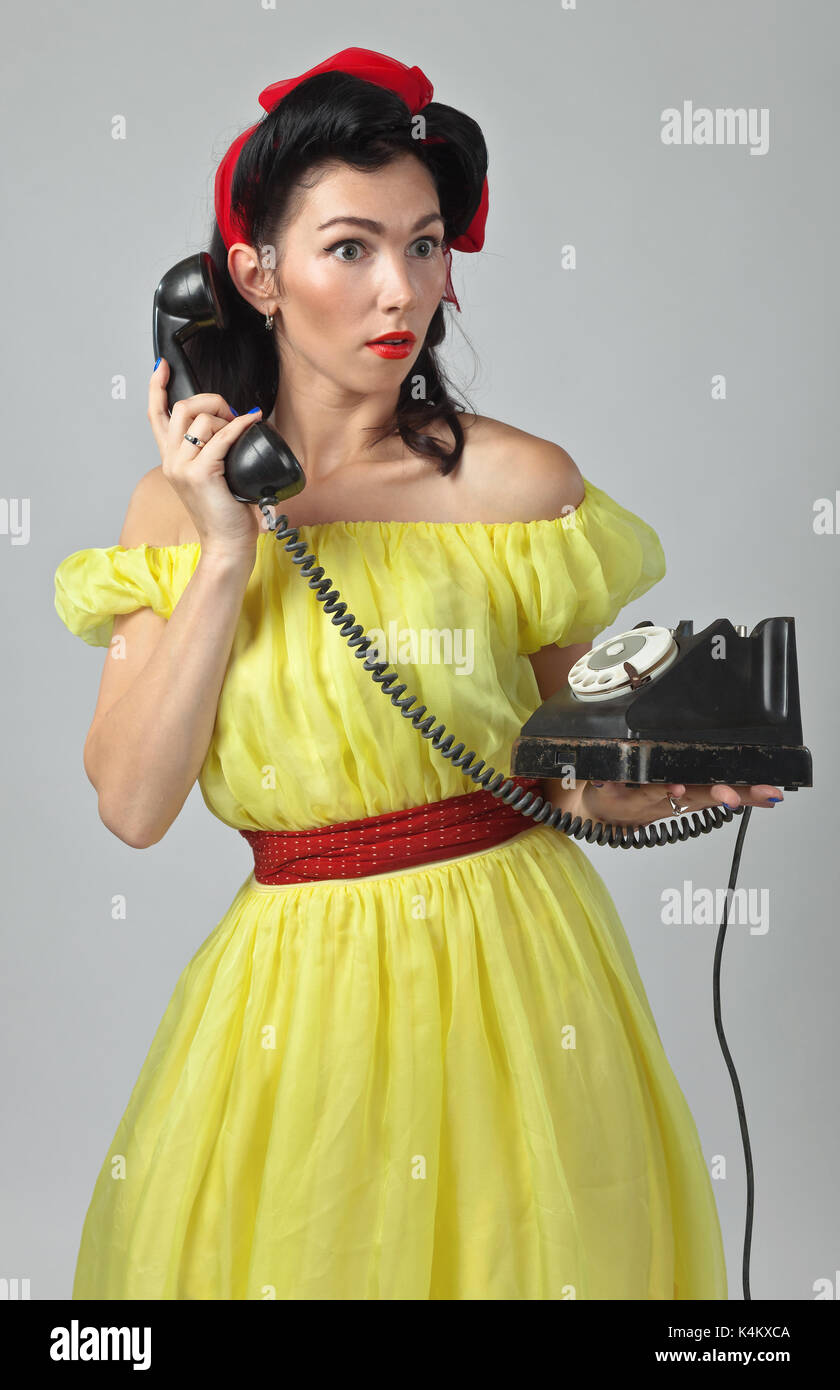 Beautiful brunette woman in pin up style with perfect hair and make up speaking via vintage ...