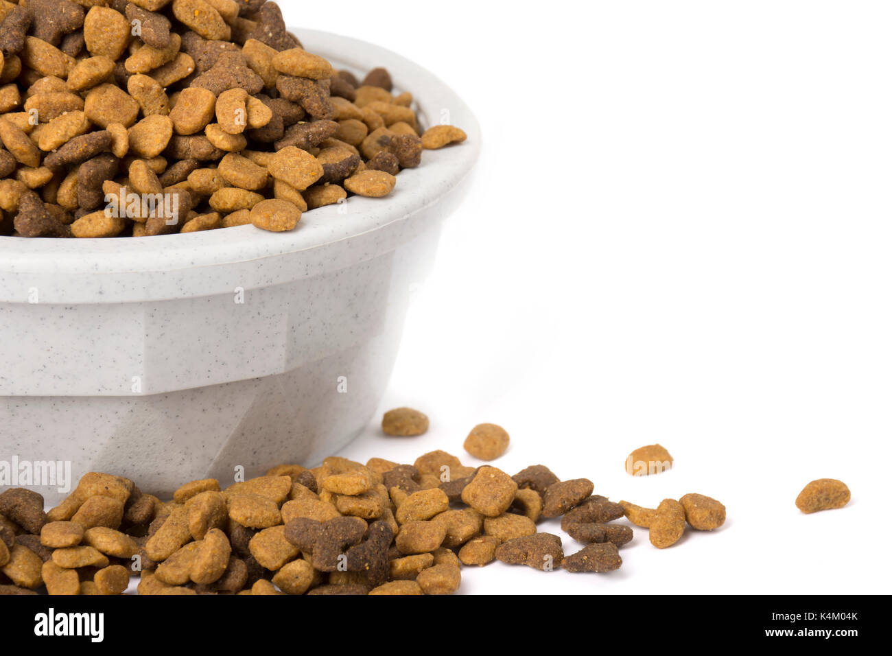 A bowl of dry cat food, side view with food overflowing out of the bowl ...