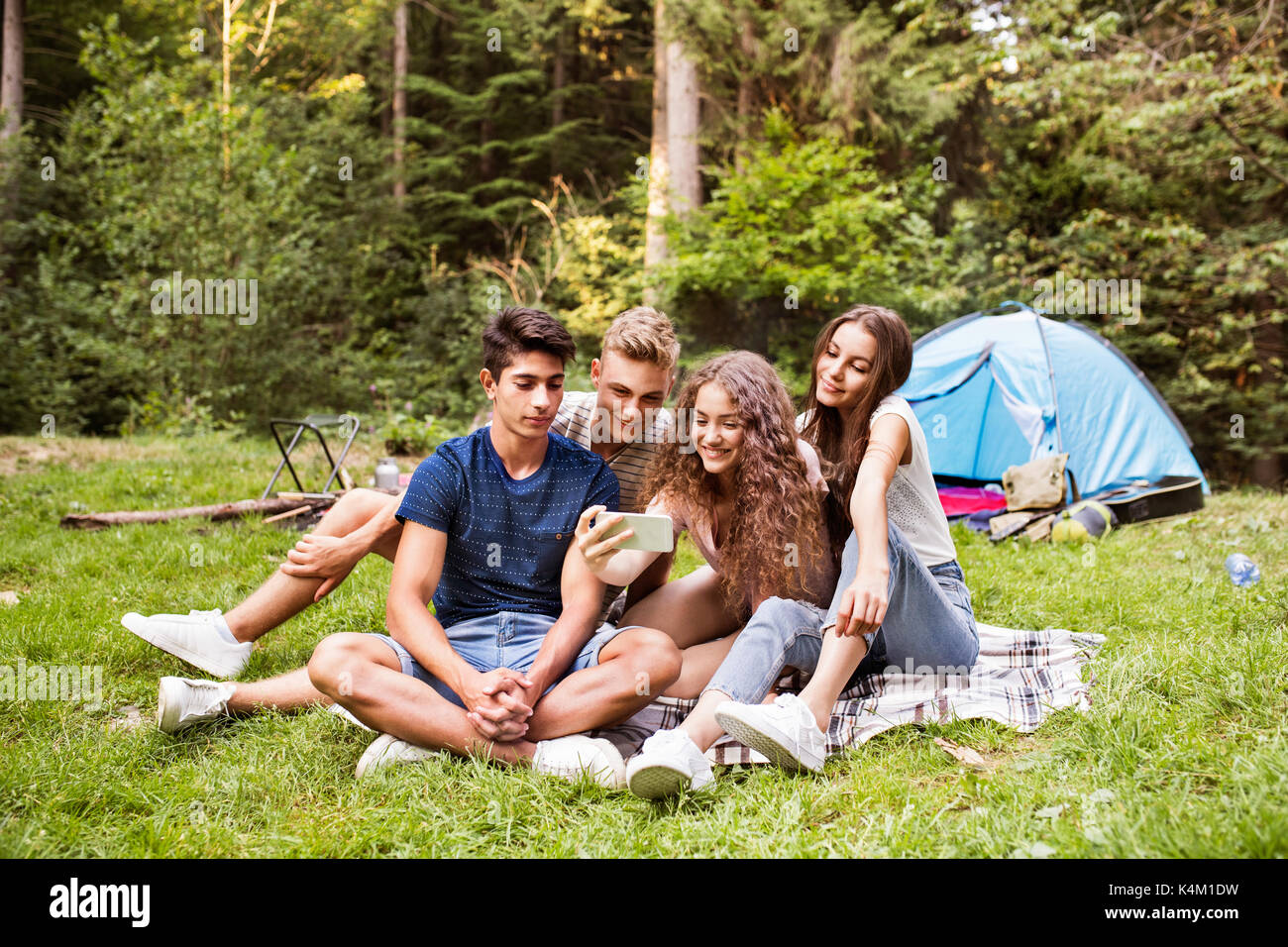Teenagers in front of tent camping in forest Stock Photo - Alamy