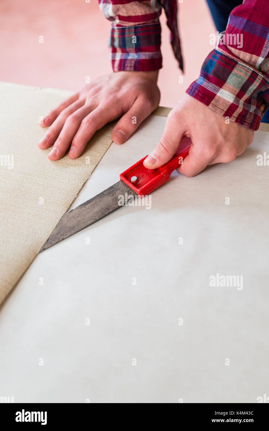 Close-up of the hands of a man cutting a new wallpaper sheet dur Stock ...