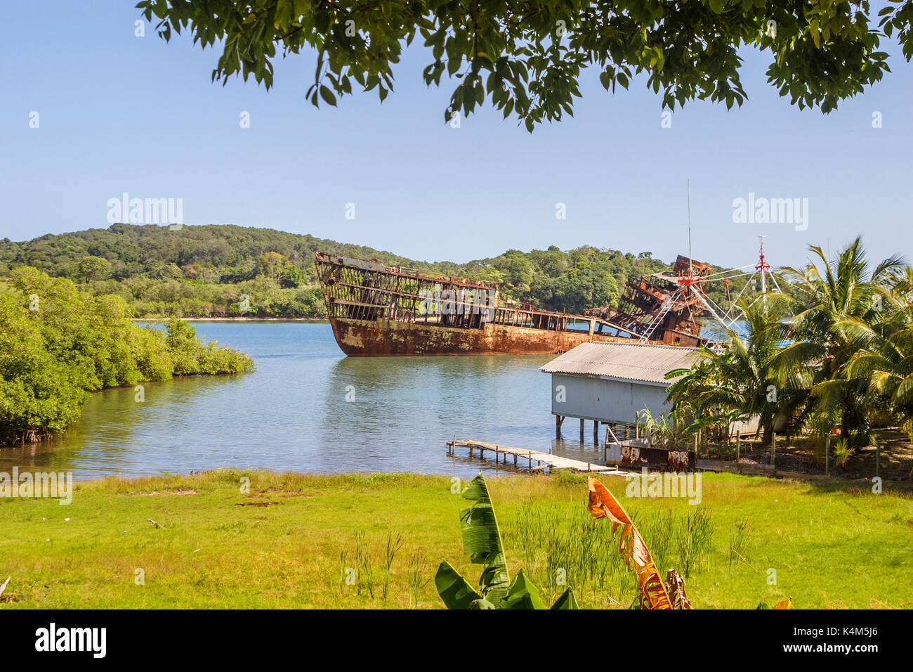 Partially submerged rusting shipwreck skeleton off the coast of scenic ...