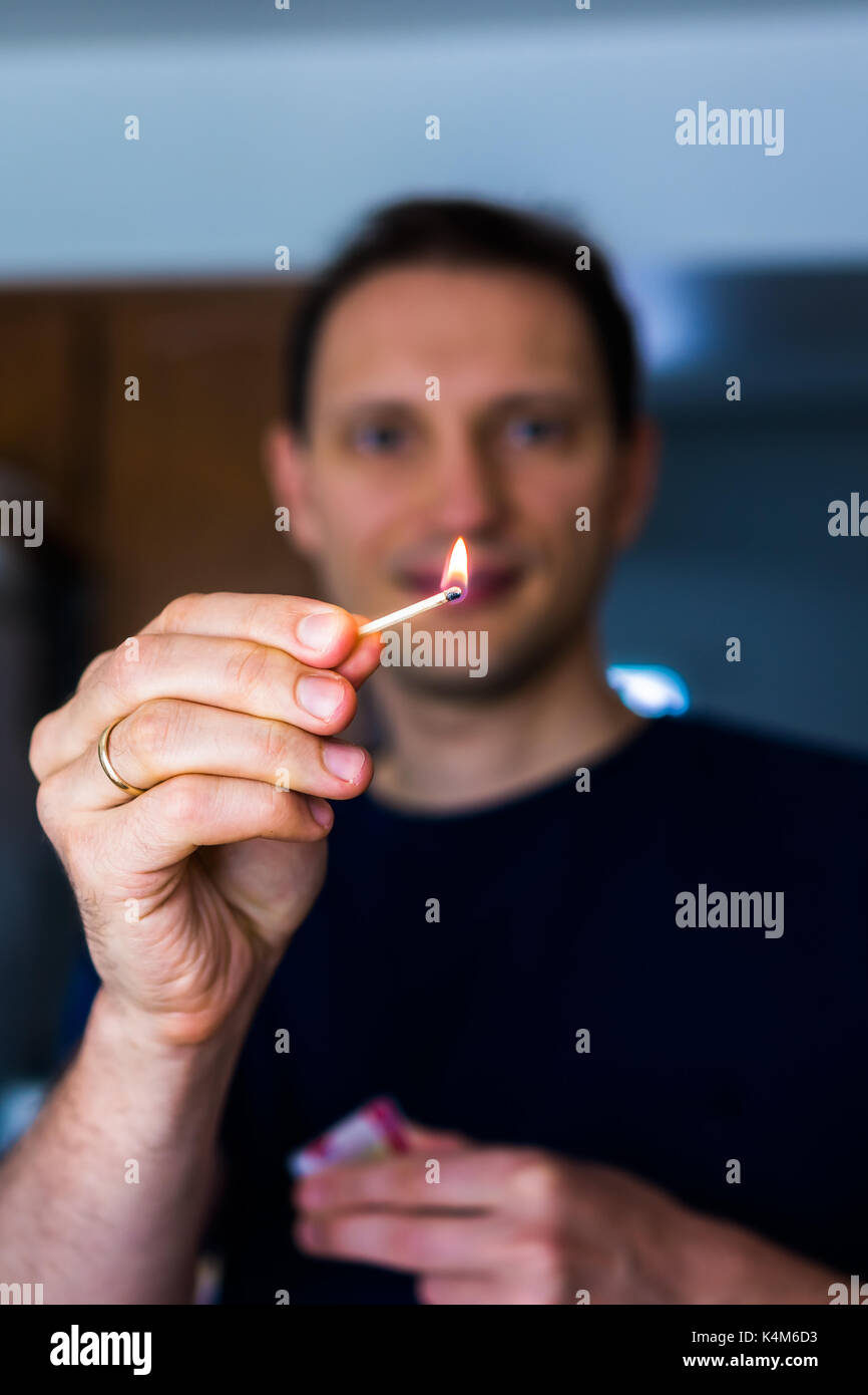 Closeup of young man holding bright lit match in hand Stock Photo - Alamy