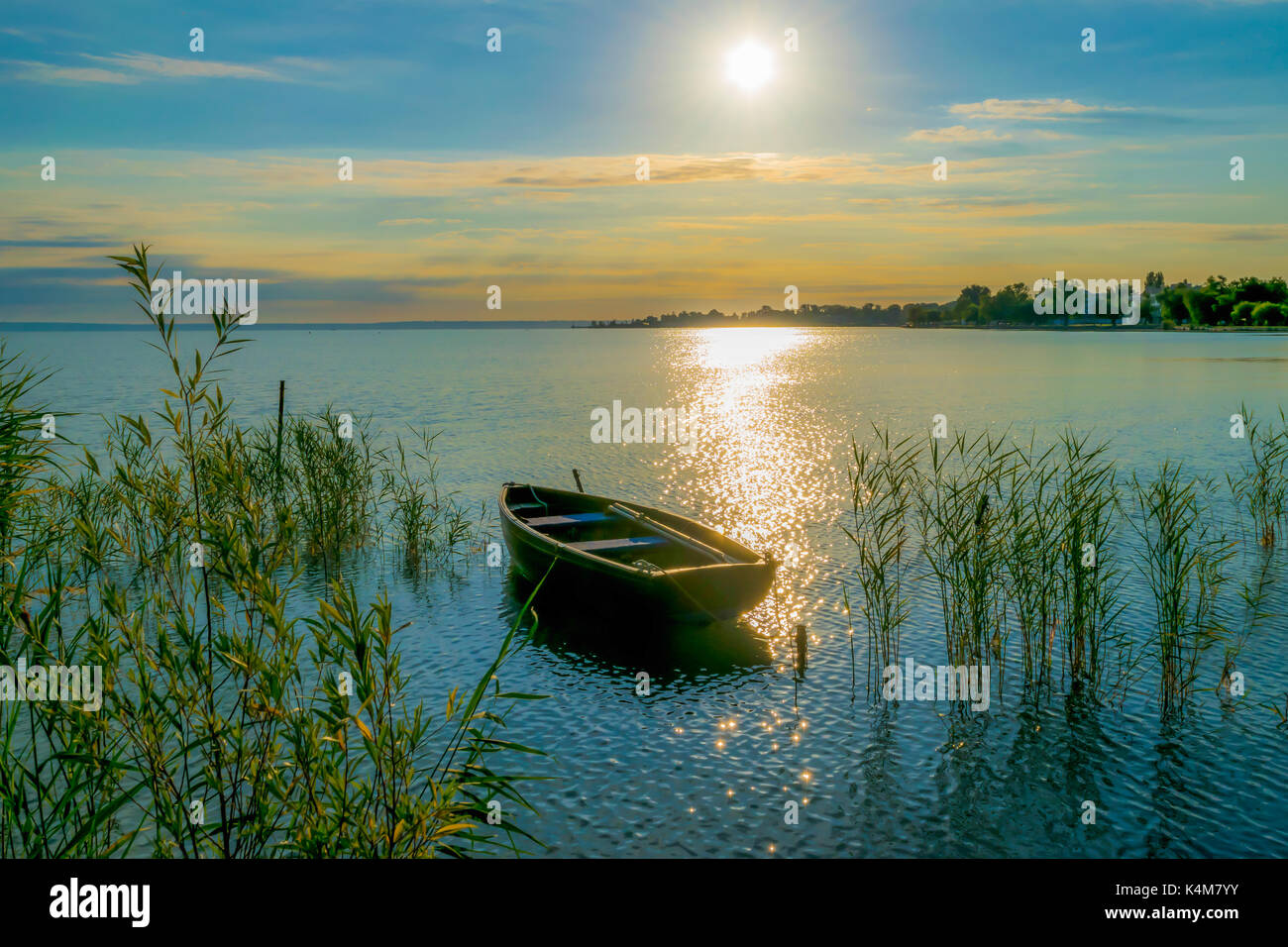 Rowing boat on lake at sunset. Small wooden rowing boat on a calm lake ...