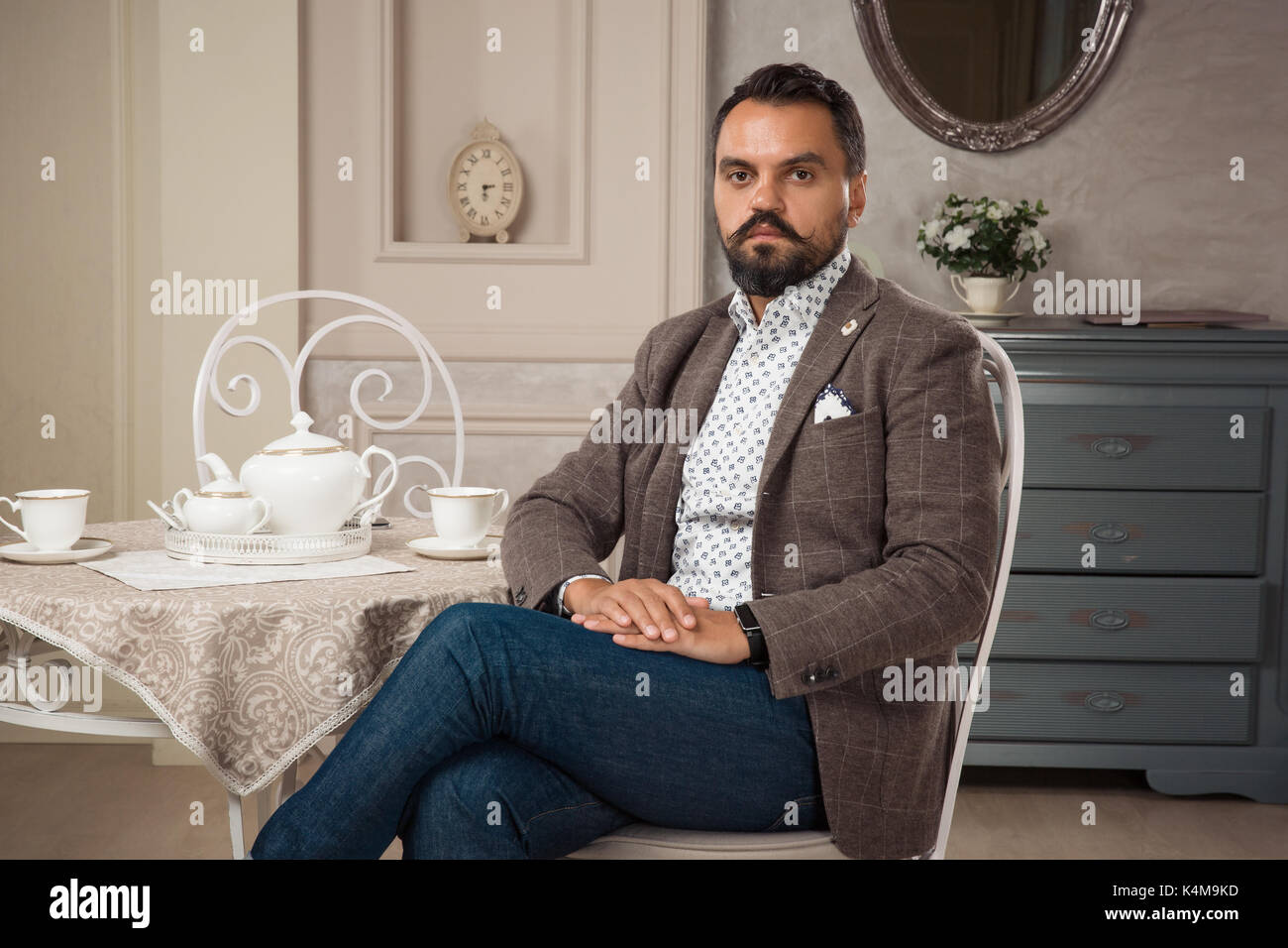 Handsome man seating on the chair at the table in retro interior ...