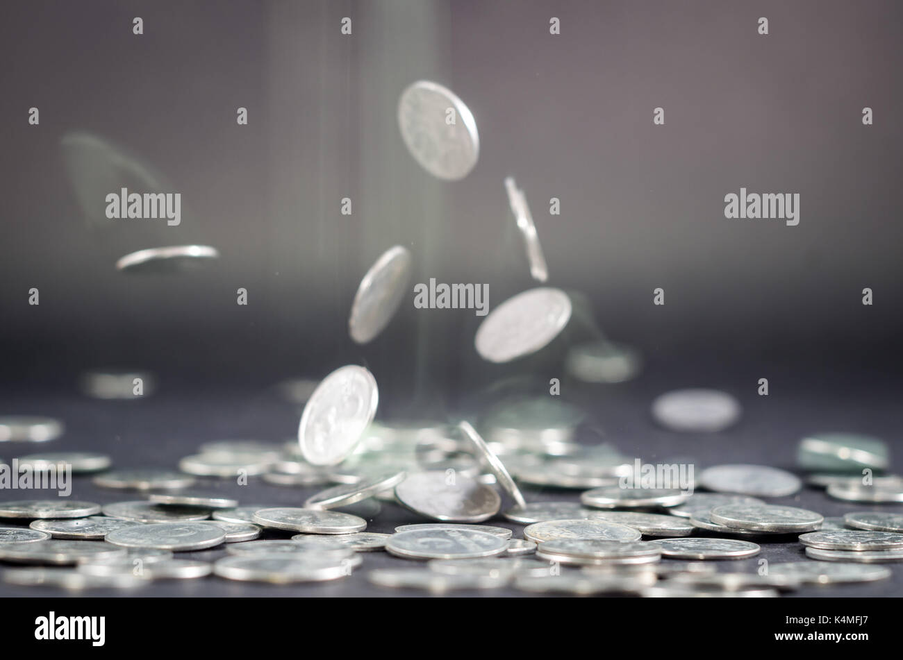 Rain of silver coins, isolated on black background, financial concept ...
