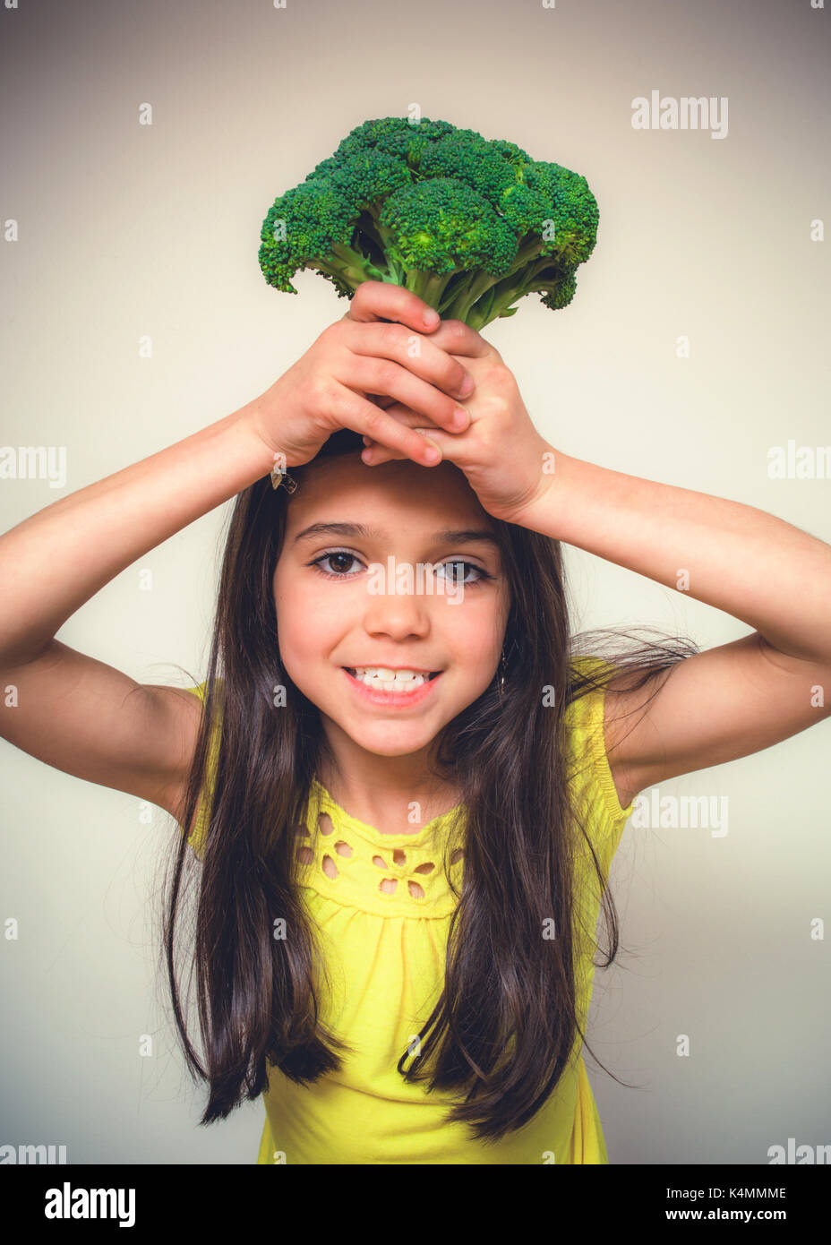 Young girl smiling and holding a broccoli bunch on her head Stock Photo ...