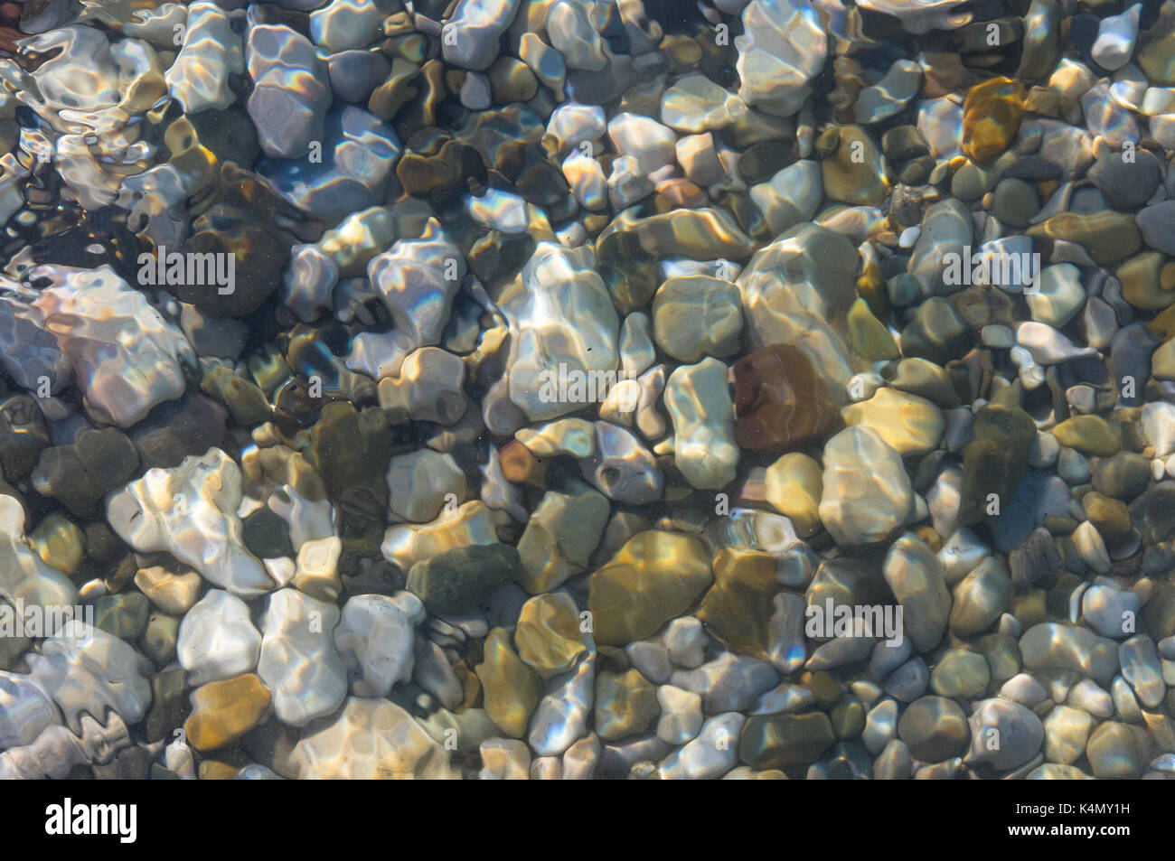 sea pebble beach with multicoloured stones, transparent waves with foam ...