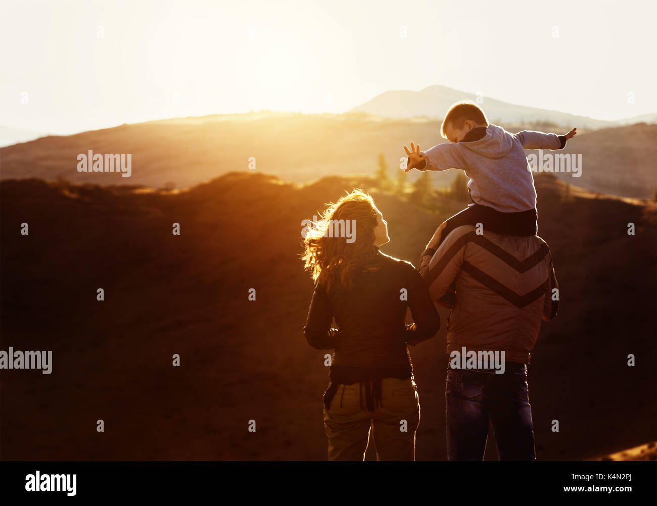 Happy family having fun at sunset time in mountains area. Space for ...