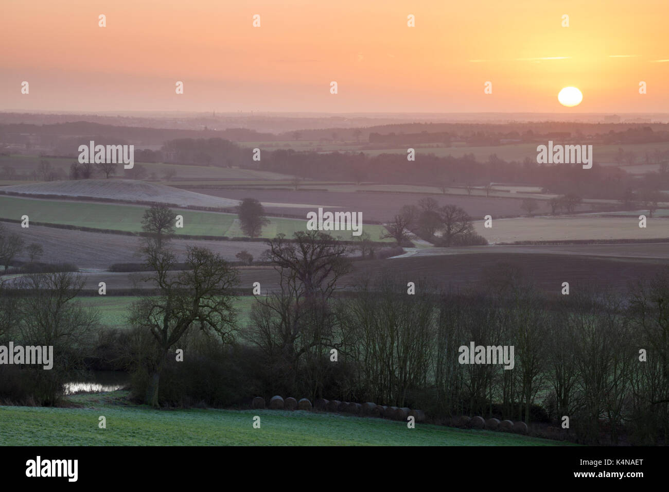 Elevated view of rolling countryside as the sun rises over the city of ...
