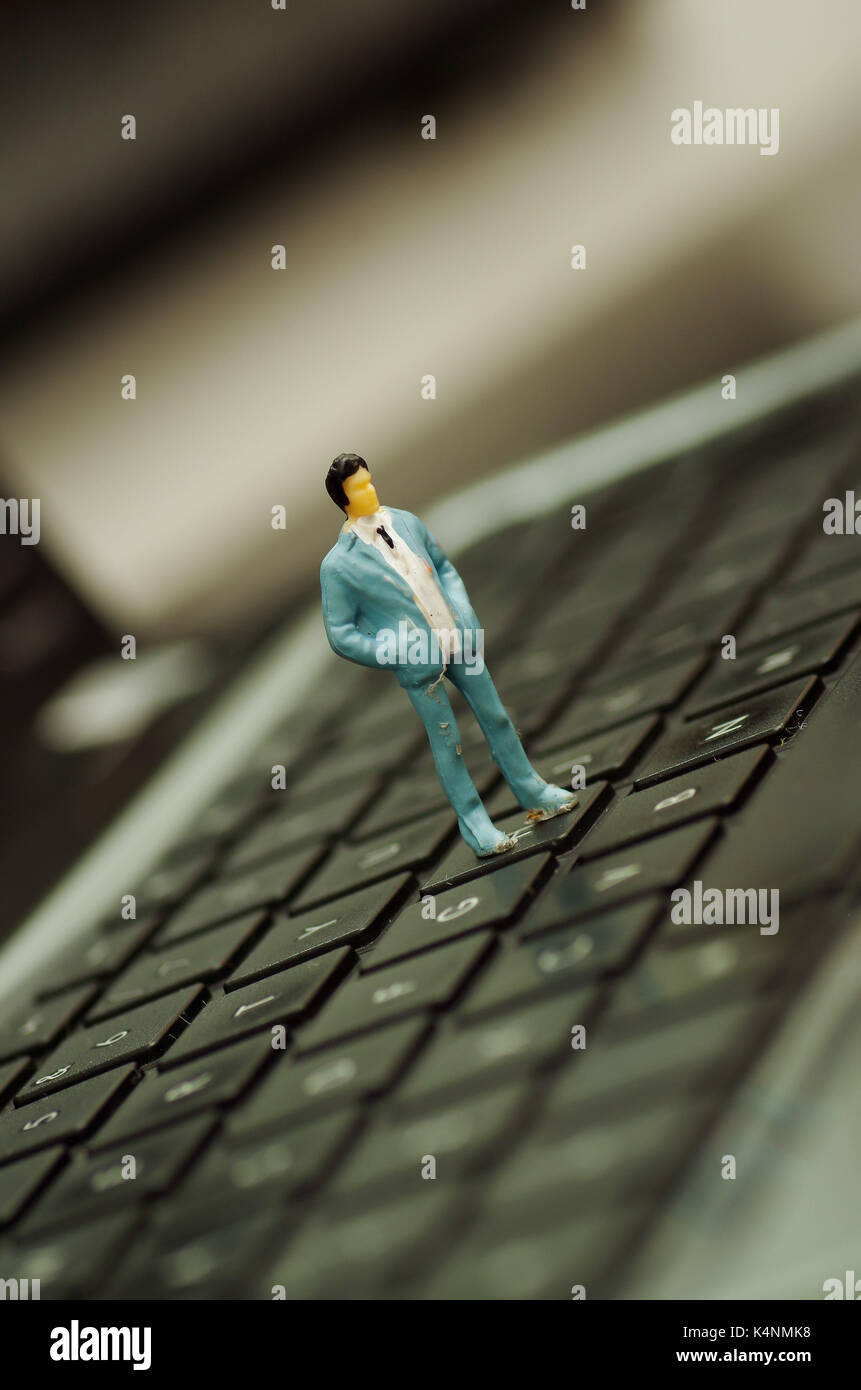Miniature little people man over a computer keyboard, in a blurred ...