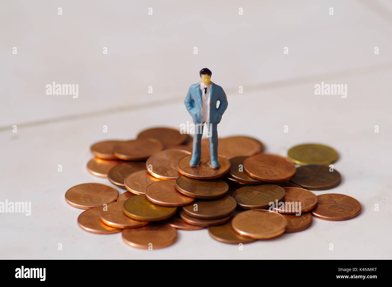 Miniature little people, man posing over a pile of one cents in a white ...