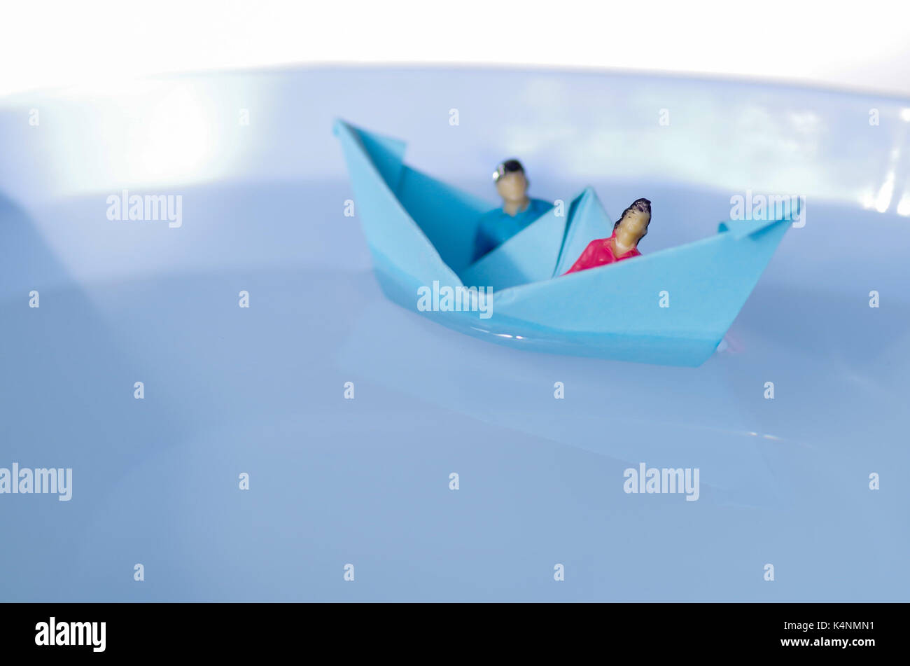 Miniature little people, couple inside of a paper boat sailing in the ...