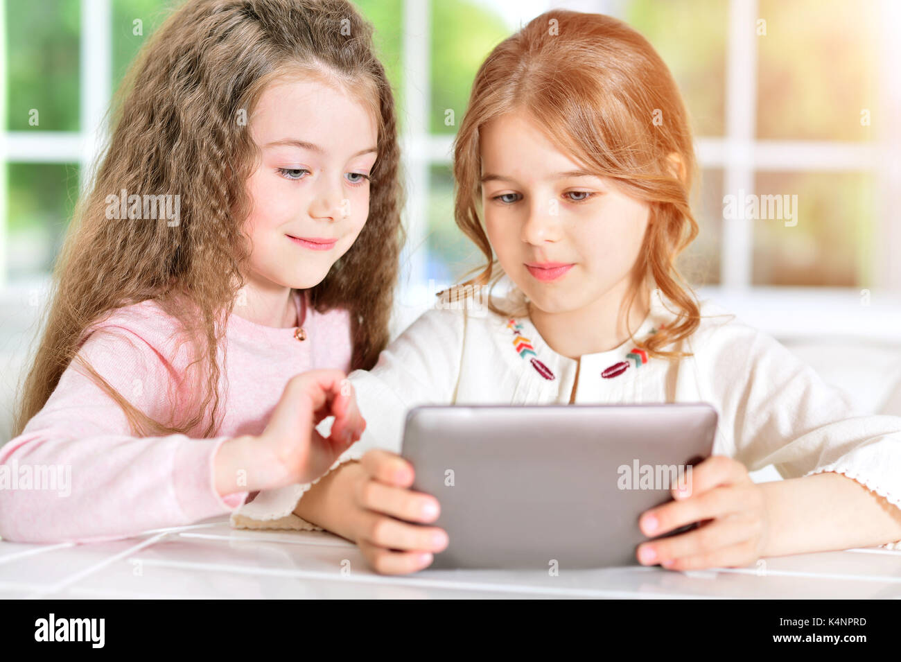 two cute little girls using digital tablet Stock Photo - Alamy