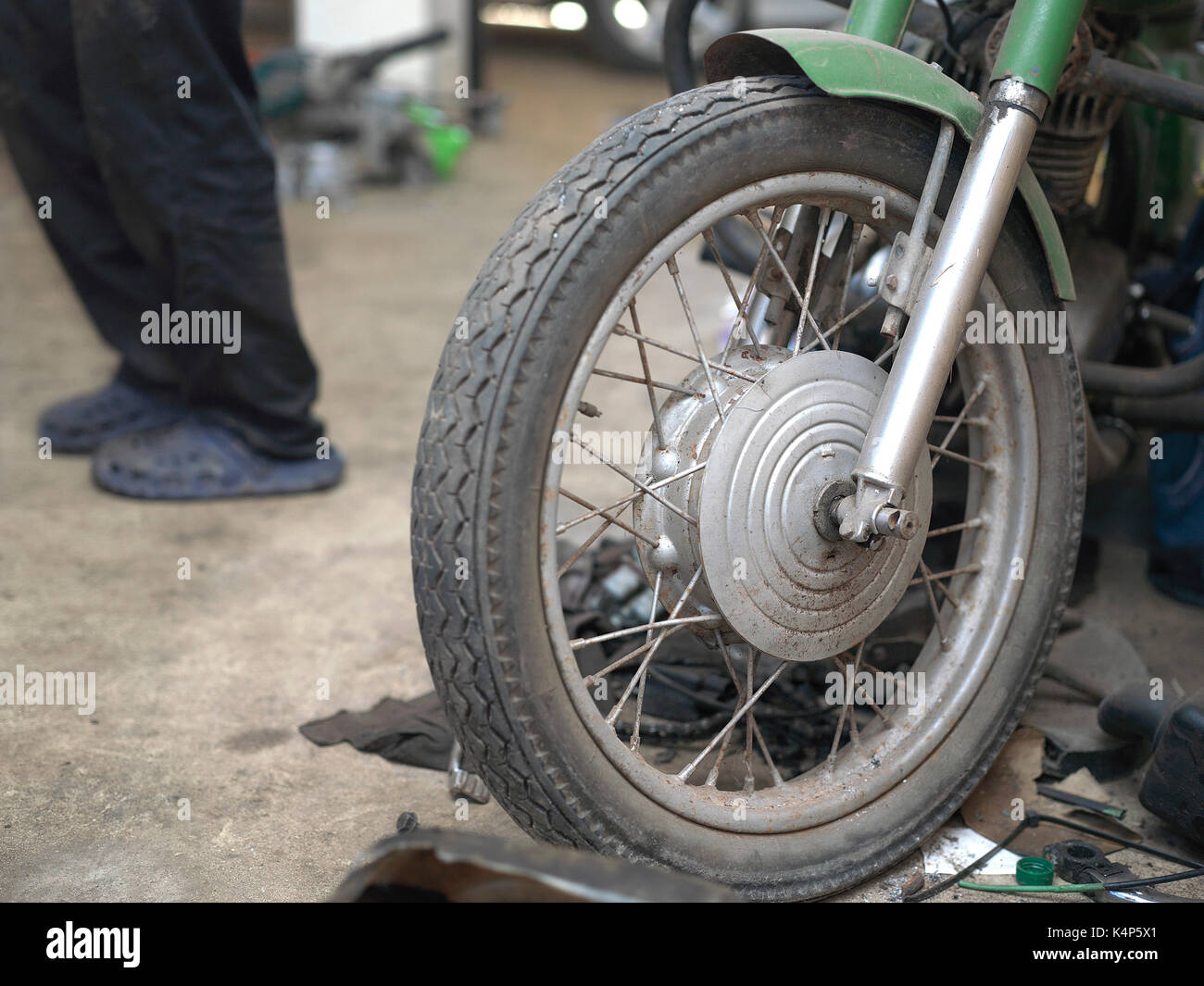 Old motorcycle needs to be repaired in a garage, mechanic legs in the ...