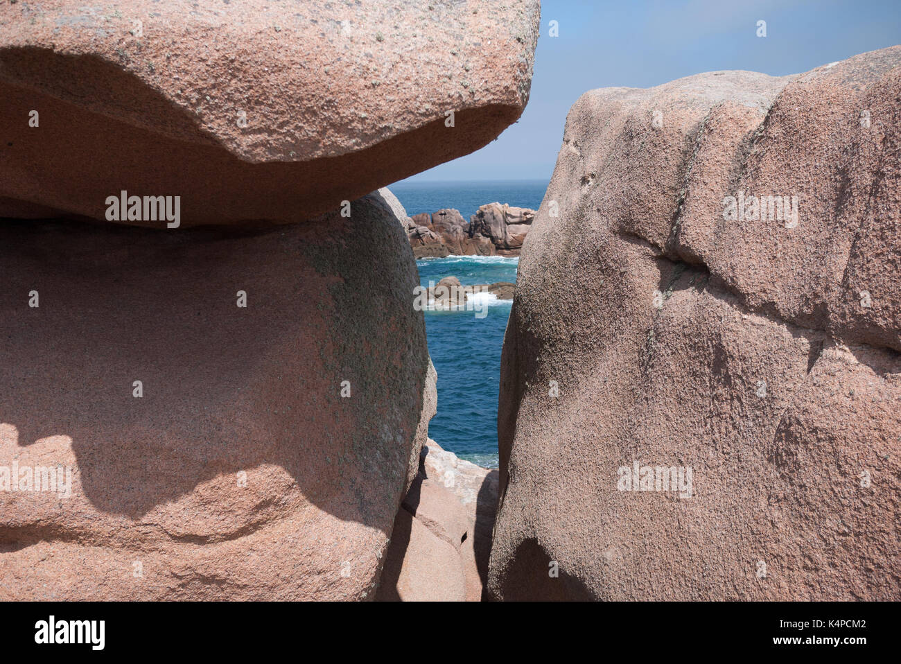 Looking through a narrow gap between an outcrop of pink coloured rocks ...