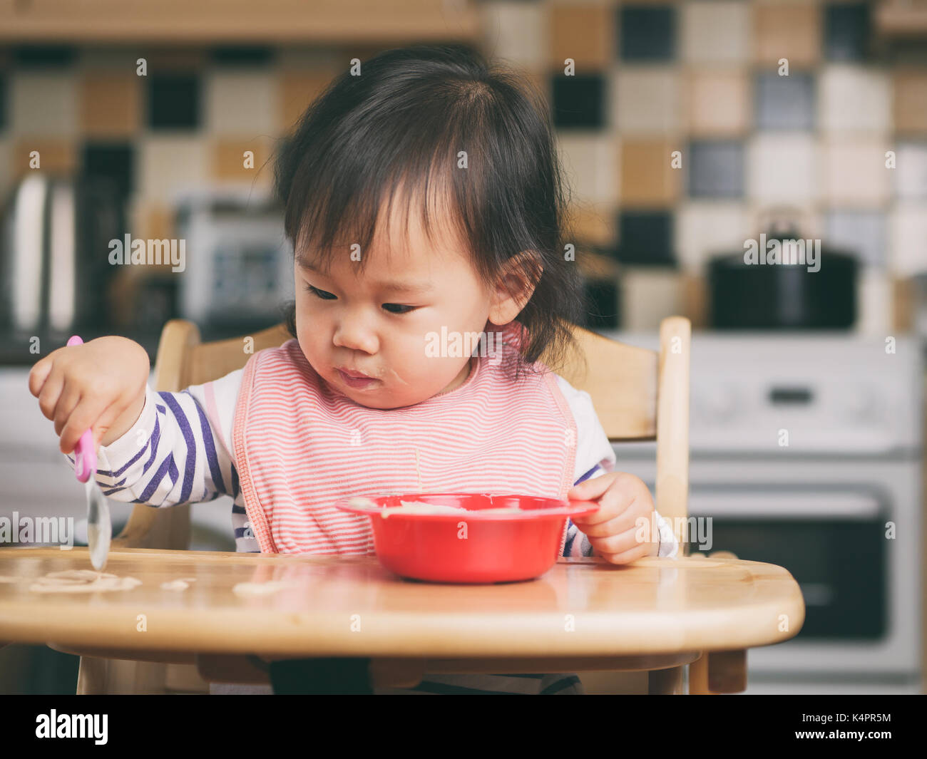 baby girl eating yoghurt at home Stock Photo - Alamy