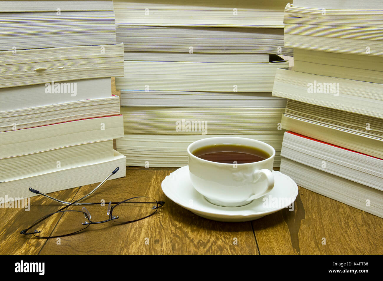 Reading glasses and cup of tea next to pile of books and novels Stock ...
