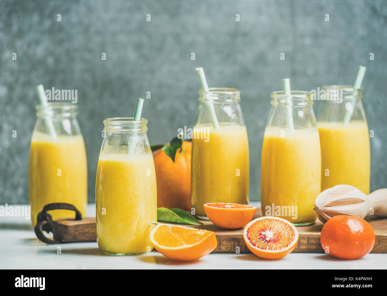 Healthy yellow smoothie in bottles over grey background Stock Photo - Alamy