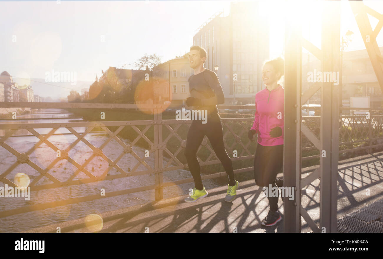 healthy young couple jogging in the city at early morning with sunrise ...