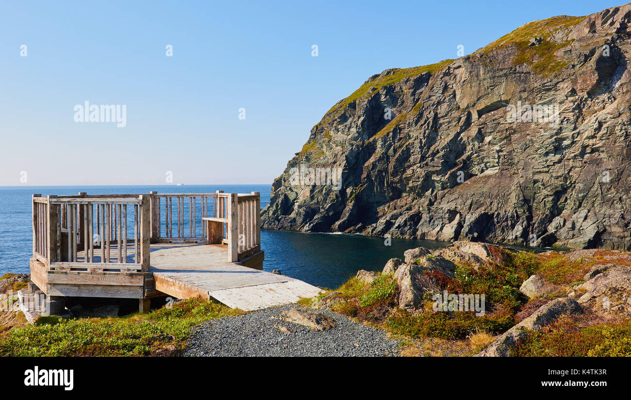 Wooden viewing platform above the Atlantic coast of Canada with iceberg ...