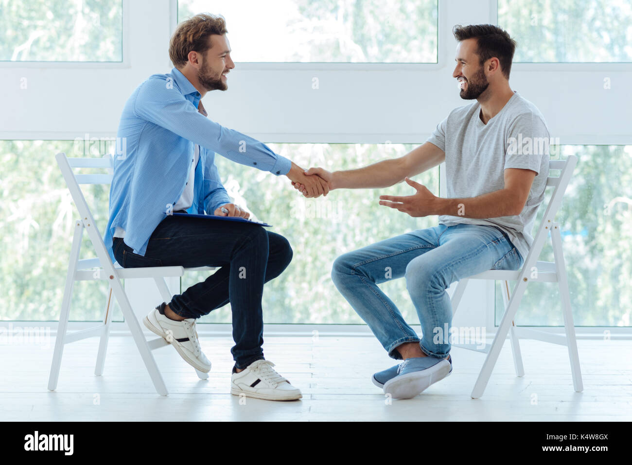 Joyful positive men shaking hands Stock Photo - Alamy