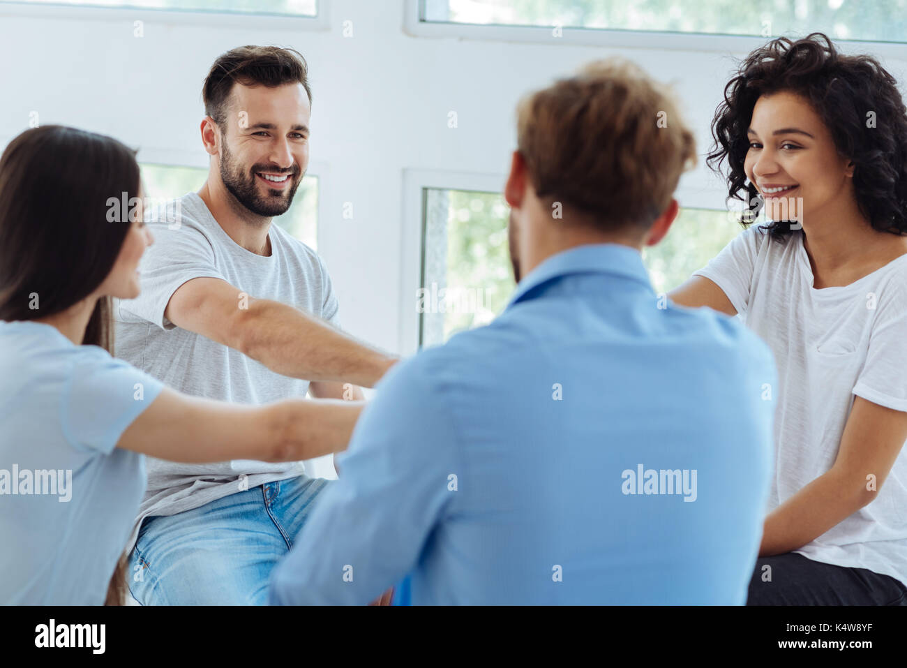 Nice delighted people holding hands together Stock Photo - Alamy