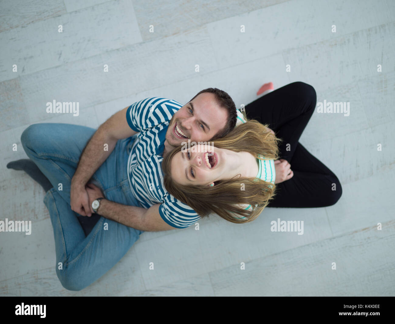 top view of Cheerful young couple sitting with back to each other on ...