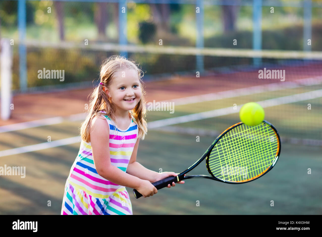 Child playing tennis on outdoor court. Little girl with tennis racket ...