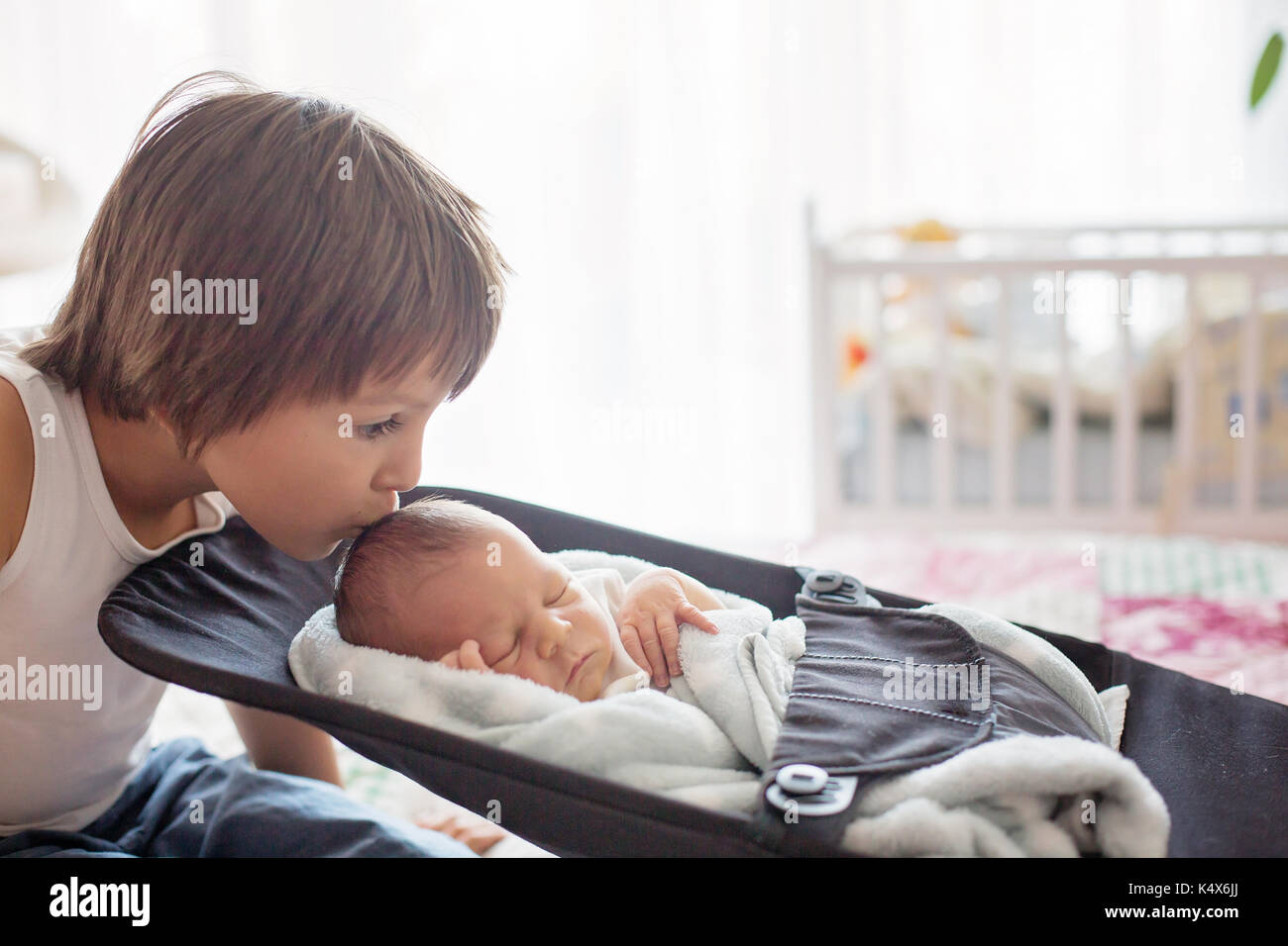 Beautiful boy, hugging with tenderness and care his newborn baby ...