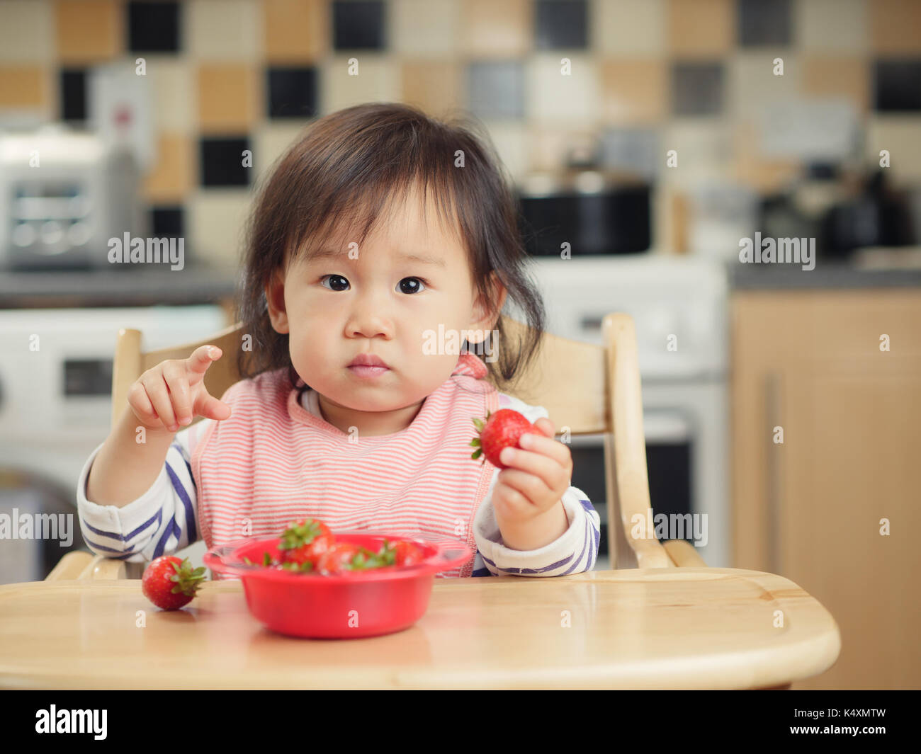 baby girl eating strawberry at home Stock Photo - Alamy