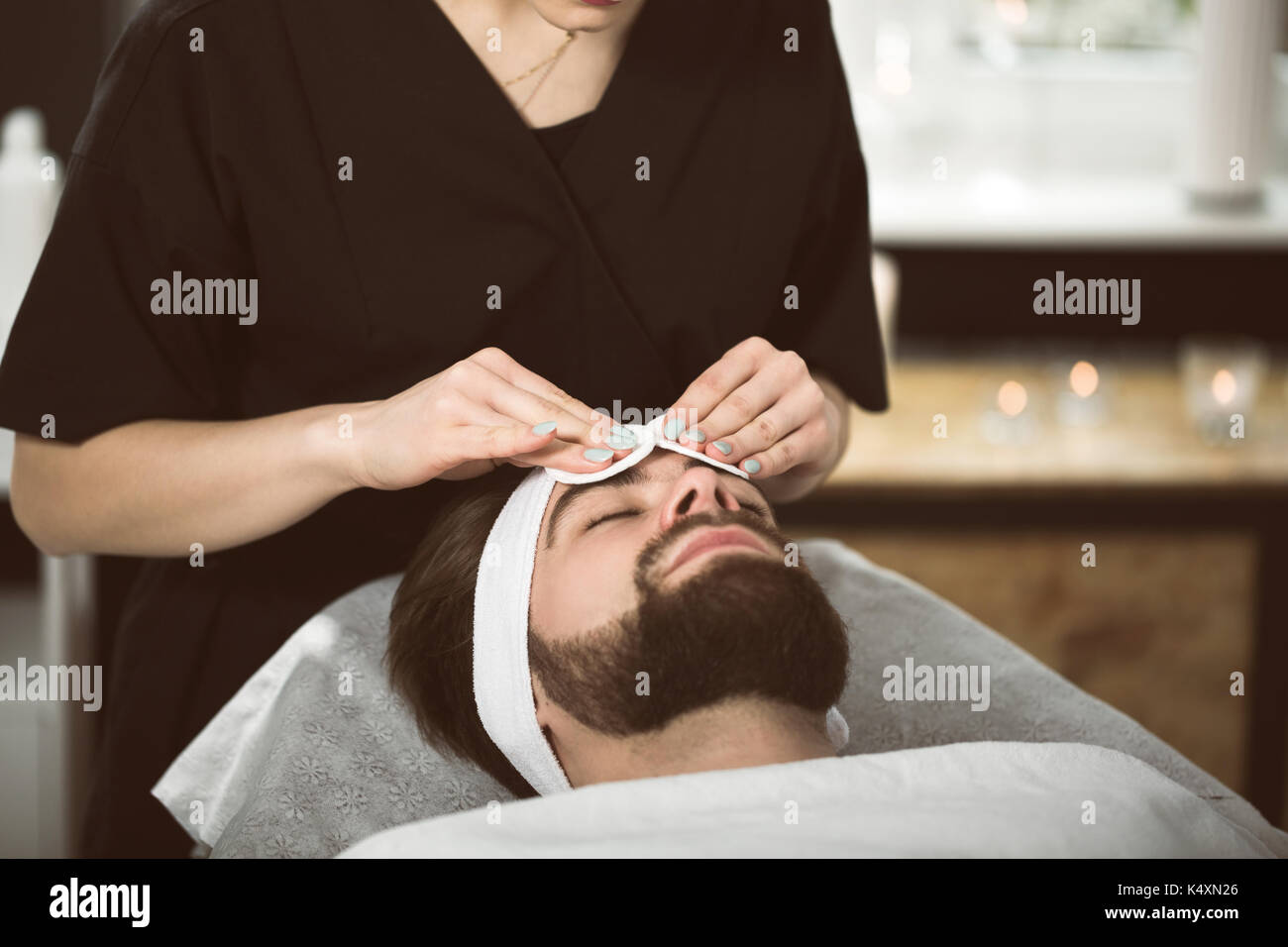 Beautician preparing man's face for a gold mask treatment Stock Photo ...