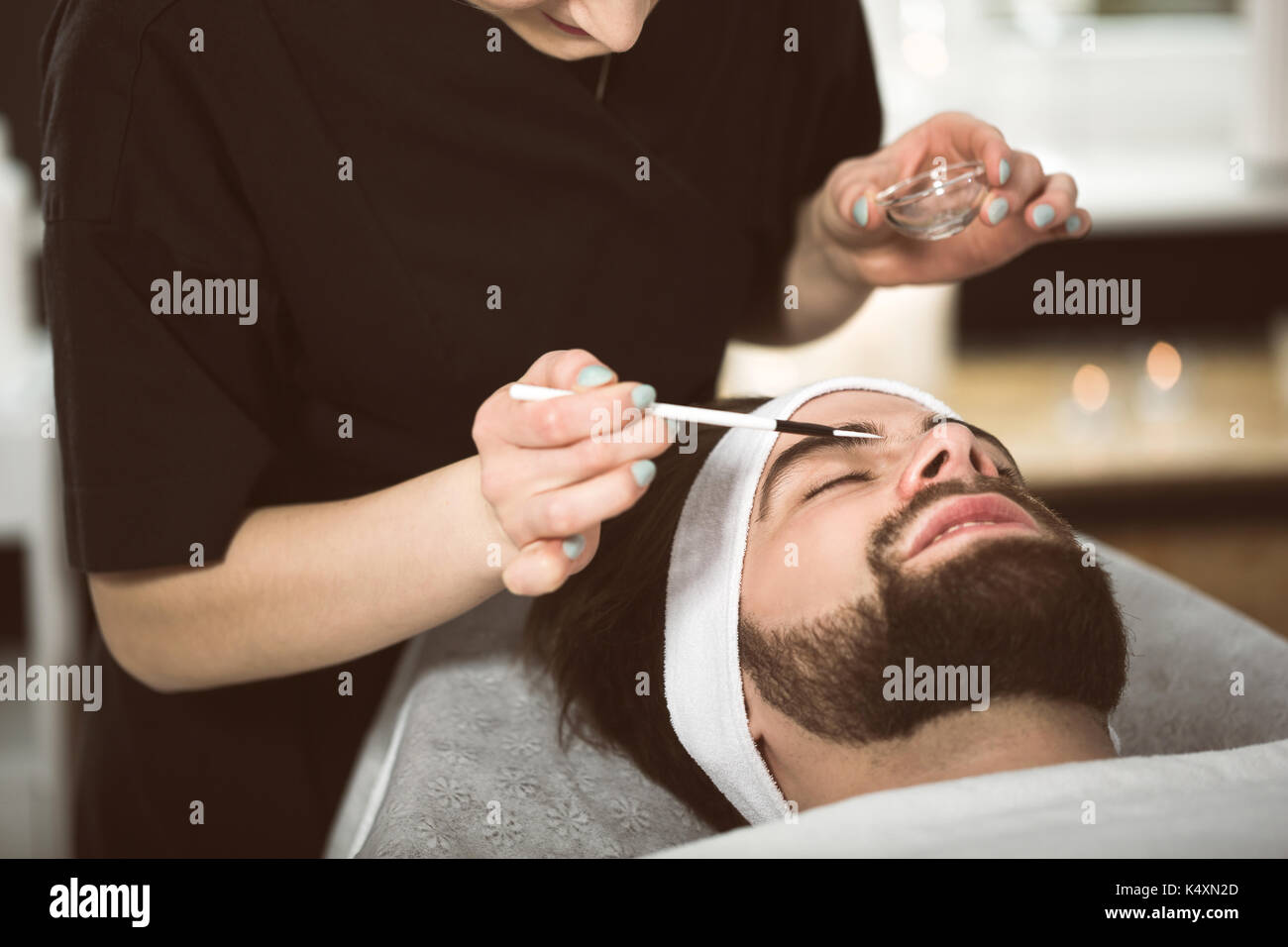 Beautician preparing man's face for a gold mask treatment Stock Photo ...