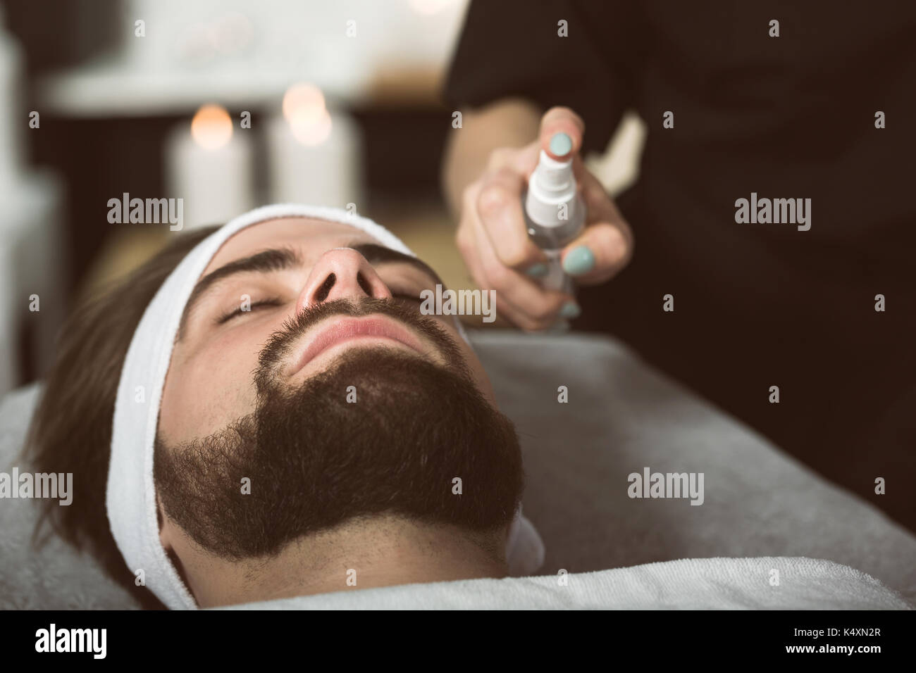 Beautician preparing man's face for a gold mask treatment Stock Photo ...