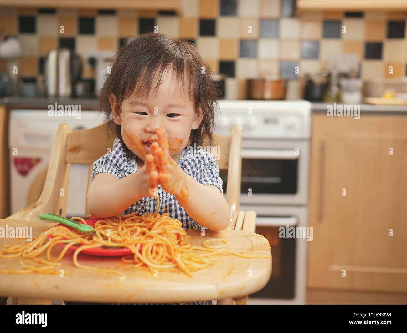 baby girl eating messy spaghetti at home Stock Photo - Alamy