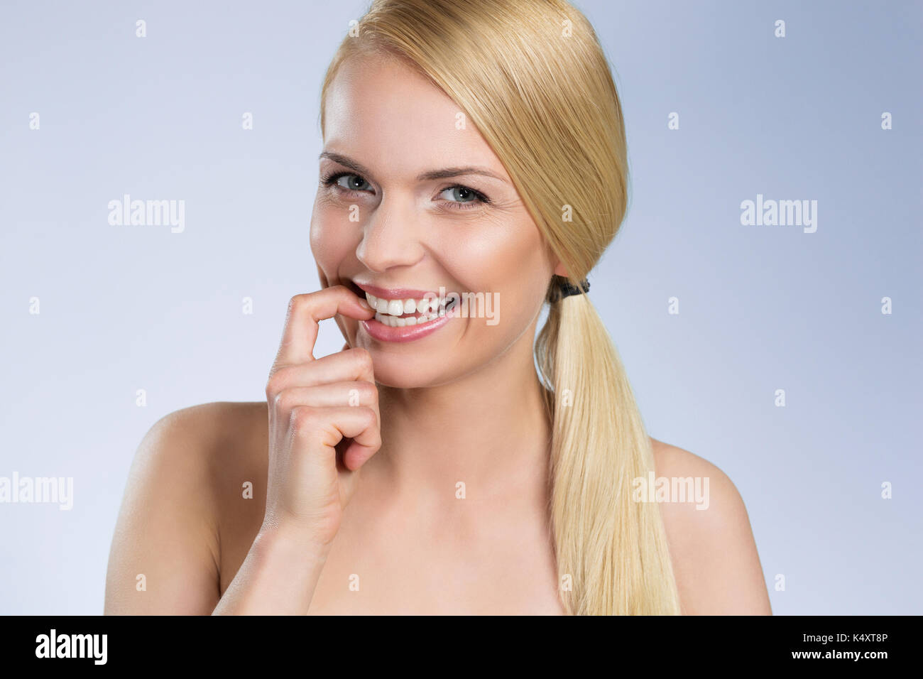 Front portrait of young blond woman biting finger smiling Stock Photo ...