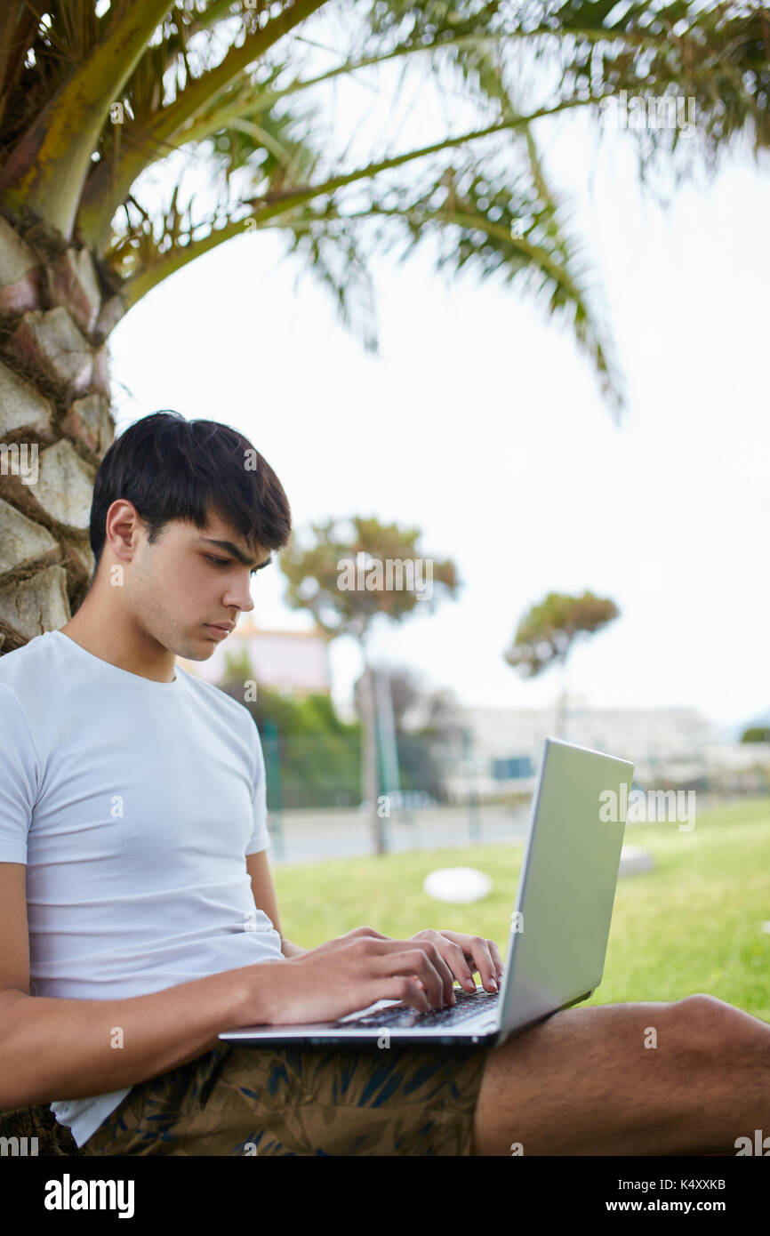 Portrait of young busy man sitting using laptop outside Stock Photo - Alamy