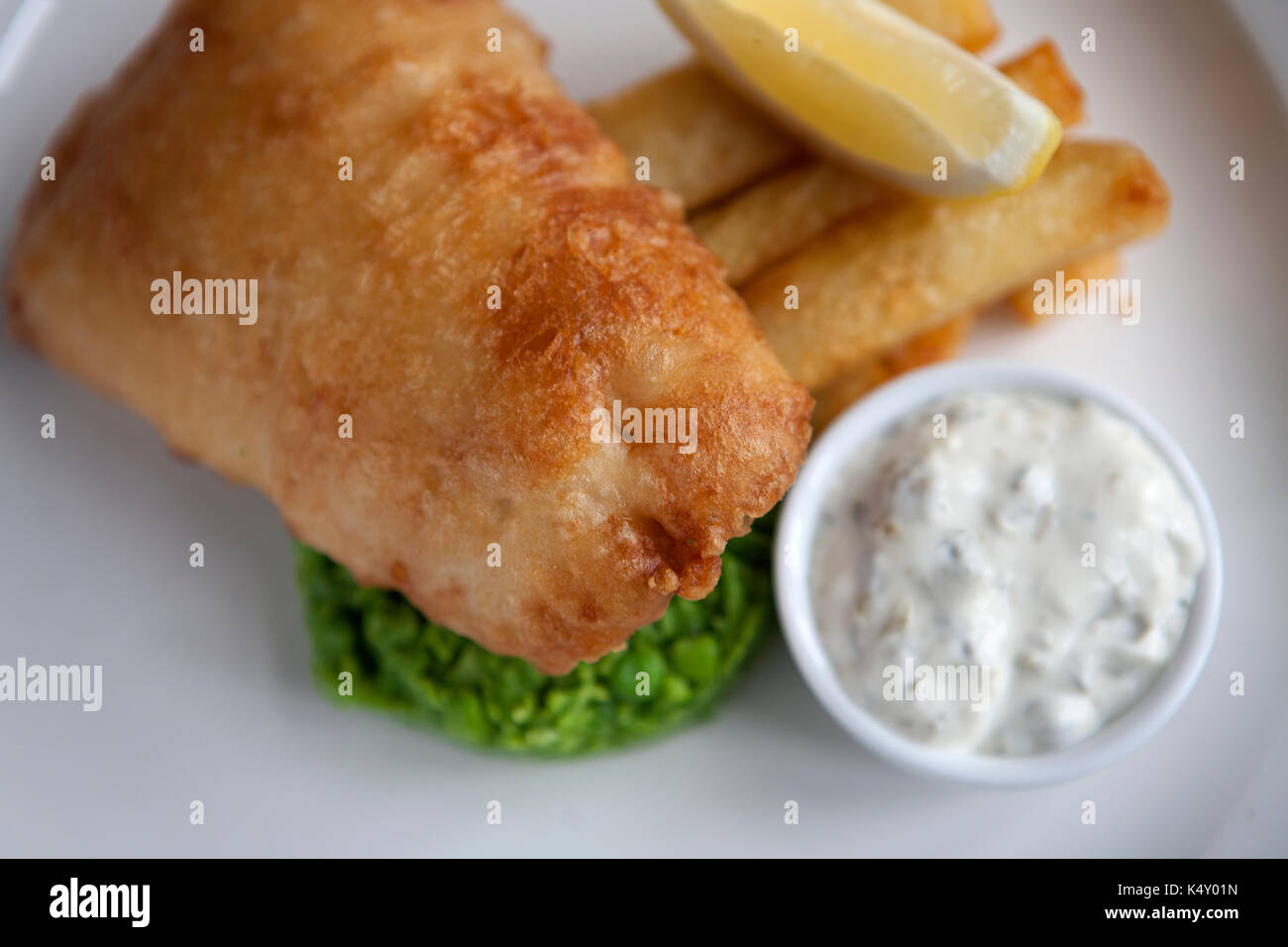 Battered fish and chips with mushy peas and tartar sauce on a plate ...