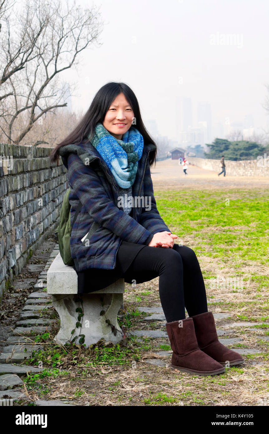 A Chinese woman sitting on a bench in the wintertime on the nanjing ...
