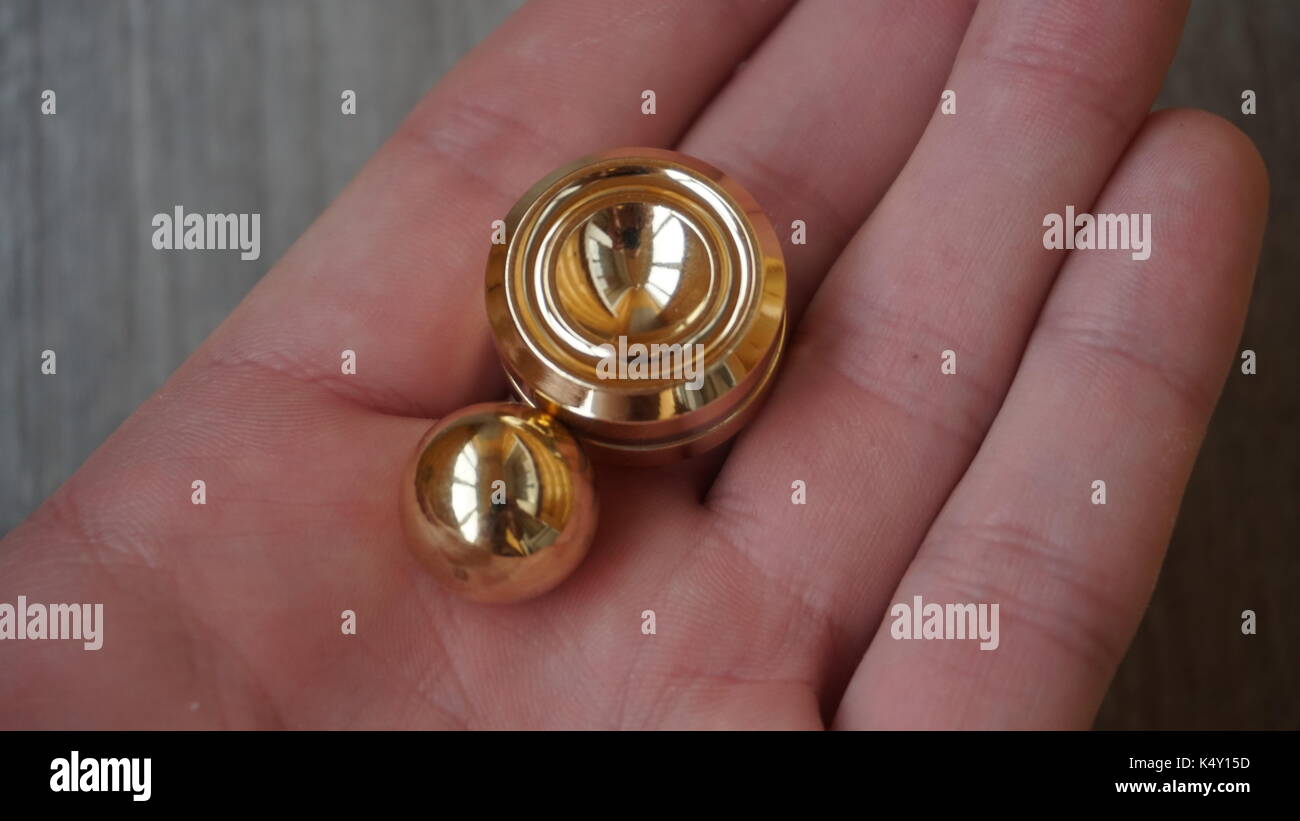 new gold fidget Orbiter,spinning in the hand of a young man on gray ...
