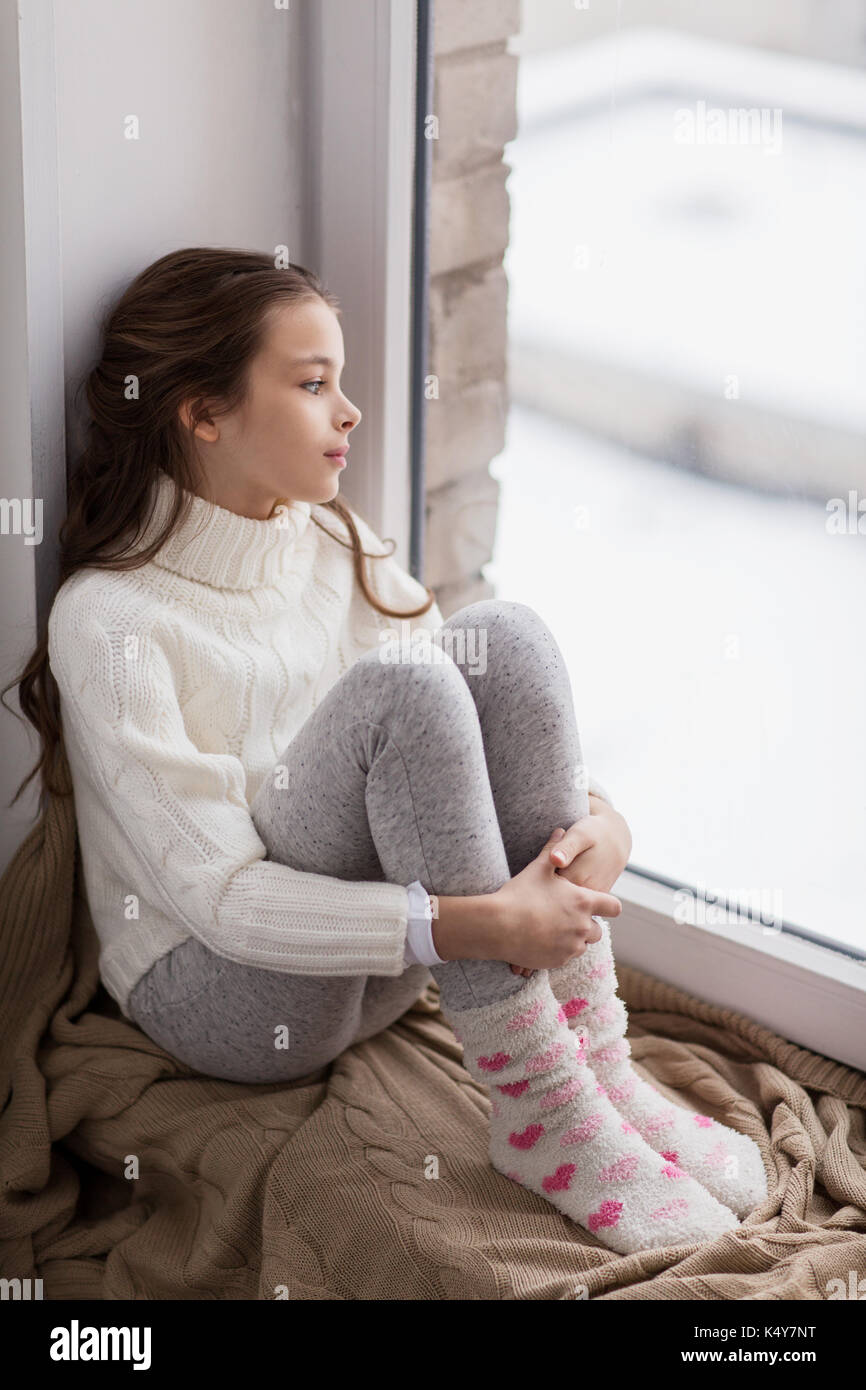 sad girl sitting on sill at home window in winter Stock Photo - Alamy