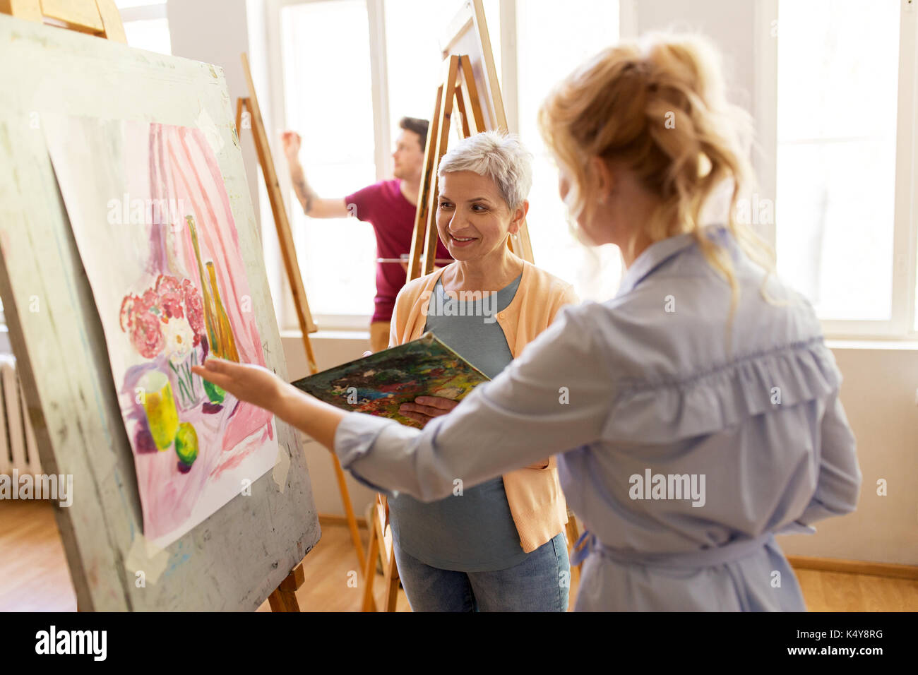 artists discussing painting on easel at art school Stock Photo - Alamy