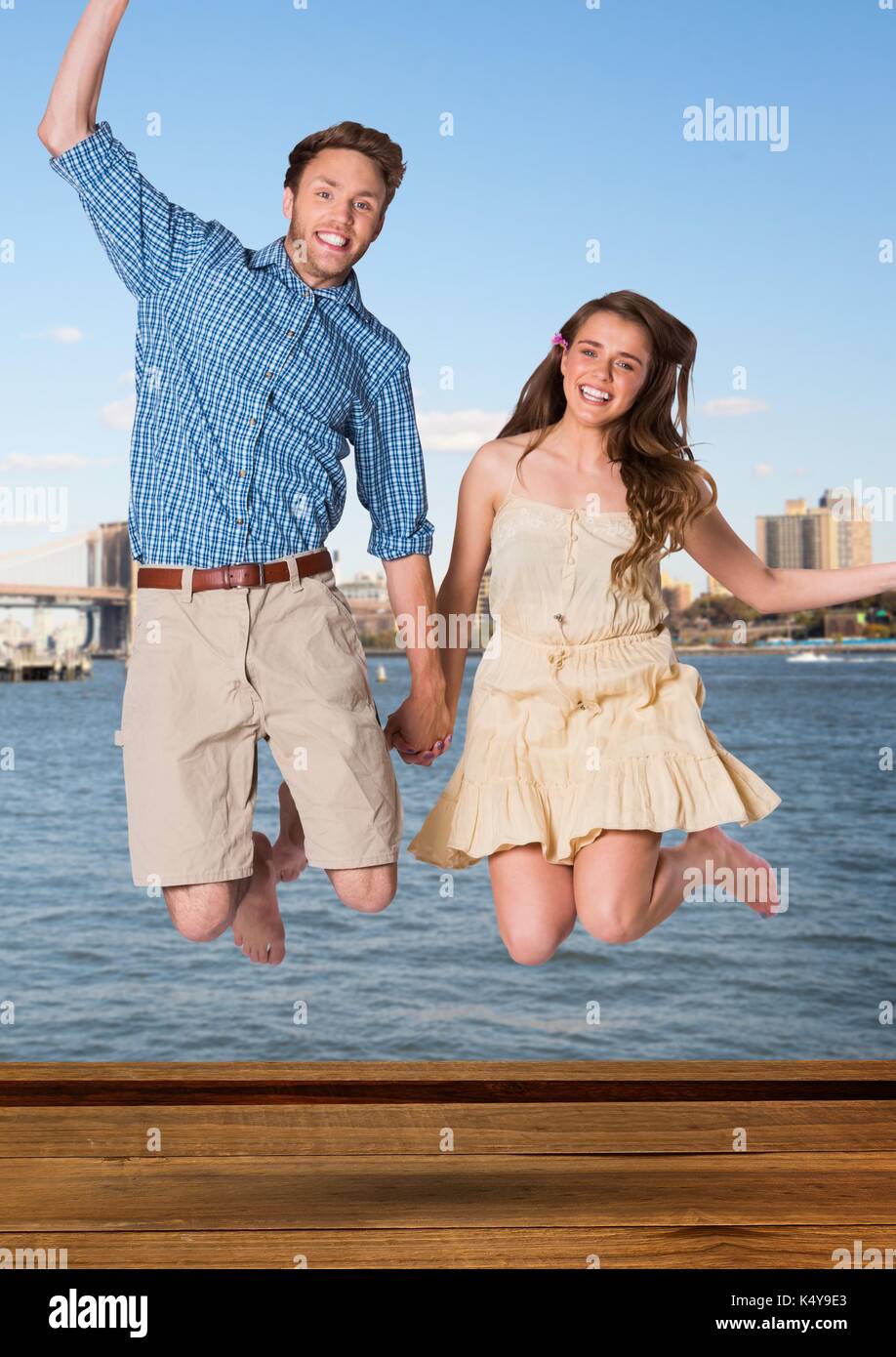 Digital composite of Couple jumping in air against water and skyline ...