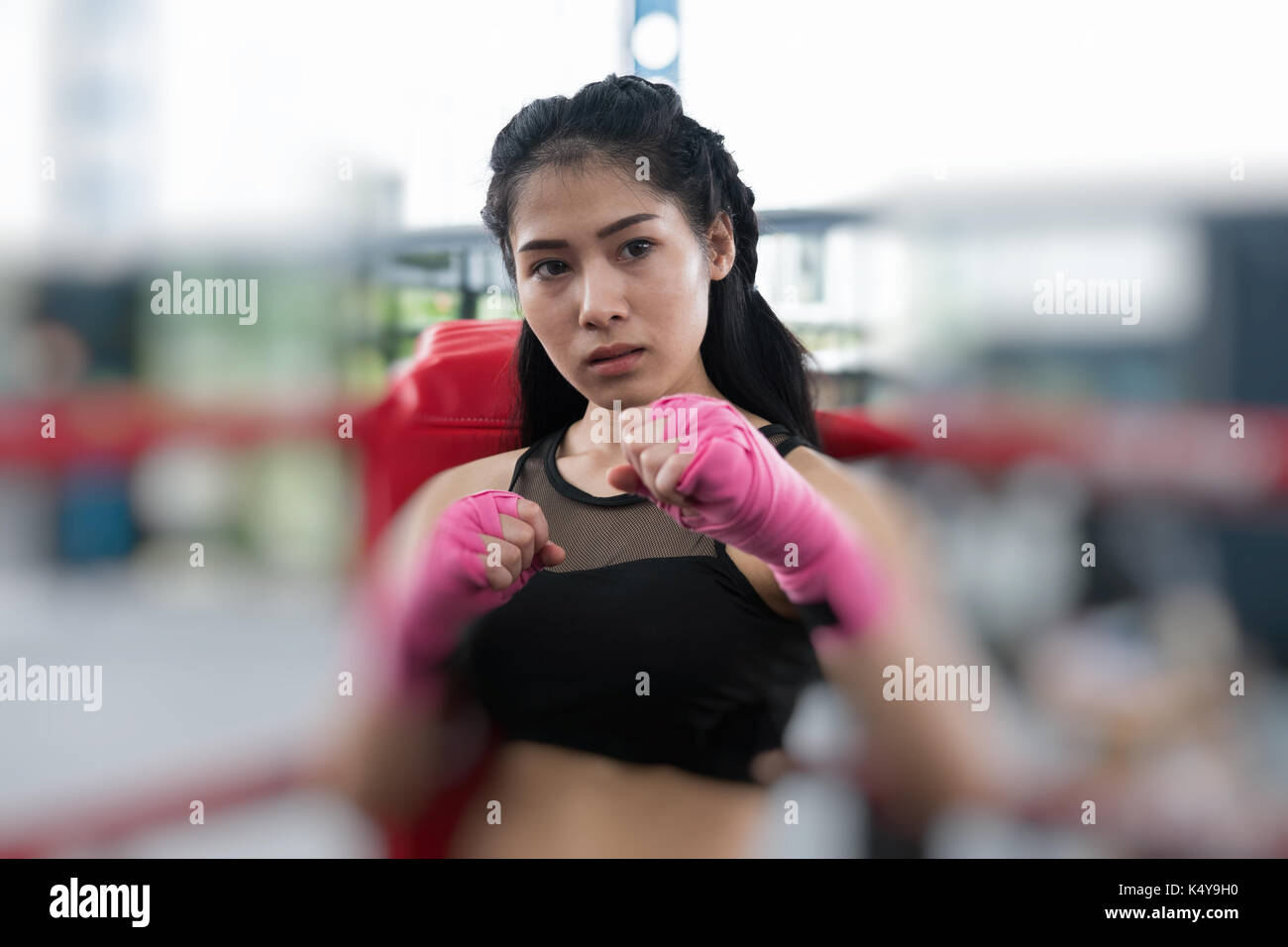 young woman posing in combat stance in fitness center. female boxer ...