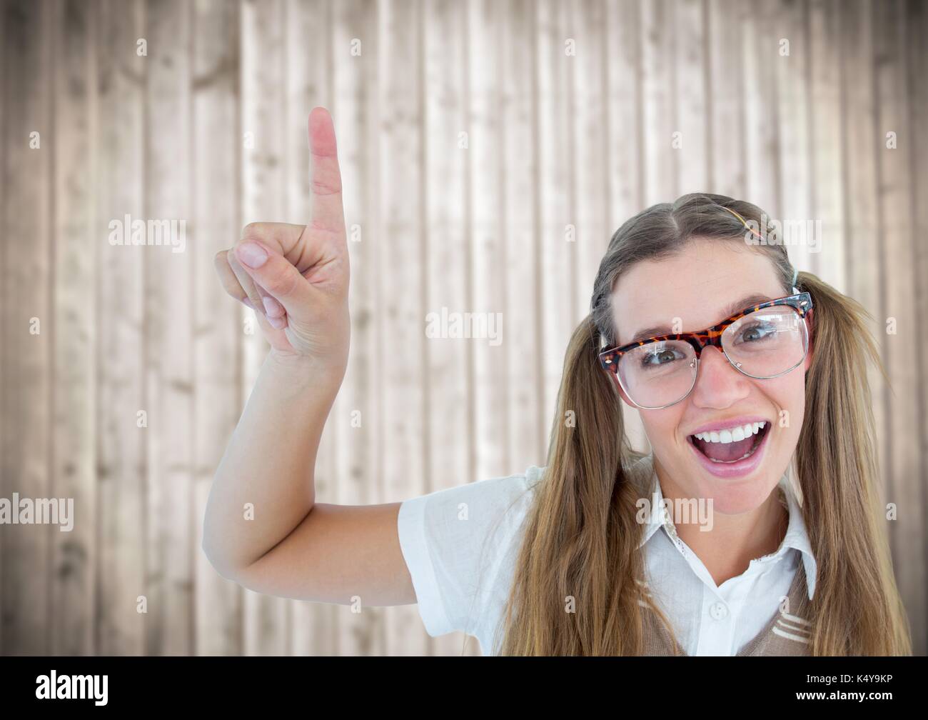 Digital composite of Nerd woman pointing up against blurry wood panel ...