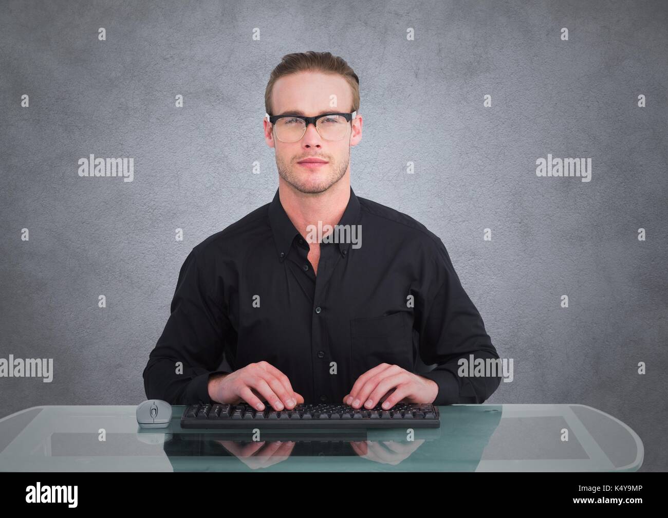 Digital composite of Nerd man at desk against grey wall with grunge ...