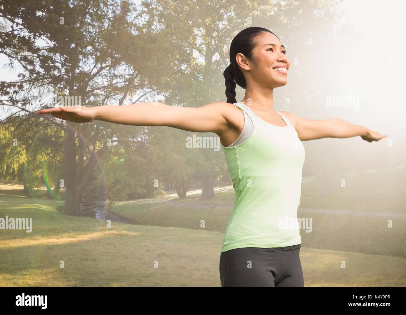 Digital composite of Woman arms outstretched against blurry park with ...
