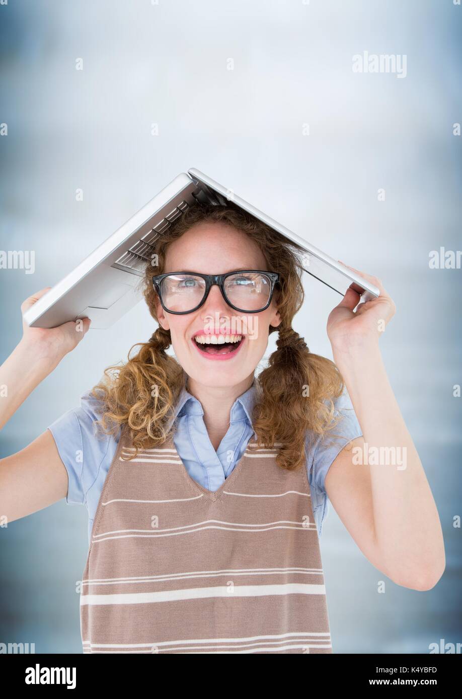 Digital composite of Nerd woman with laptop on head against blurry blue ...