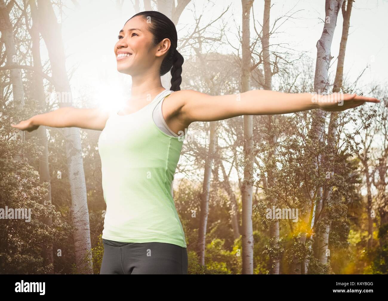 Digital composite of Woman arms outstretched against blurry trees with ...