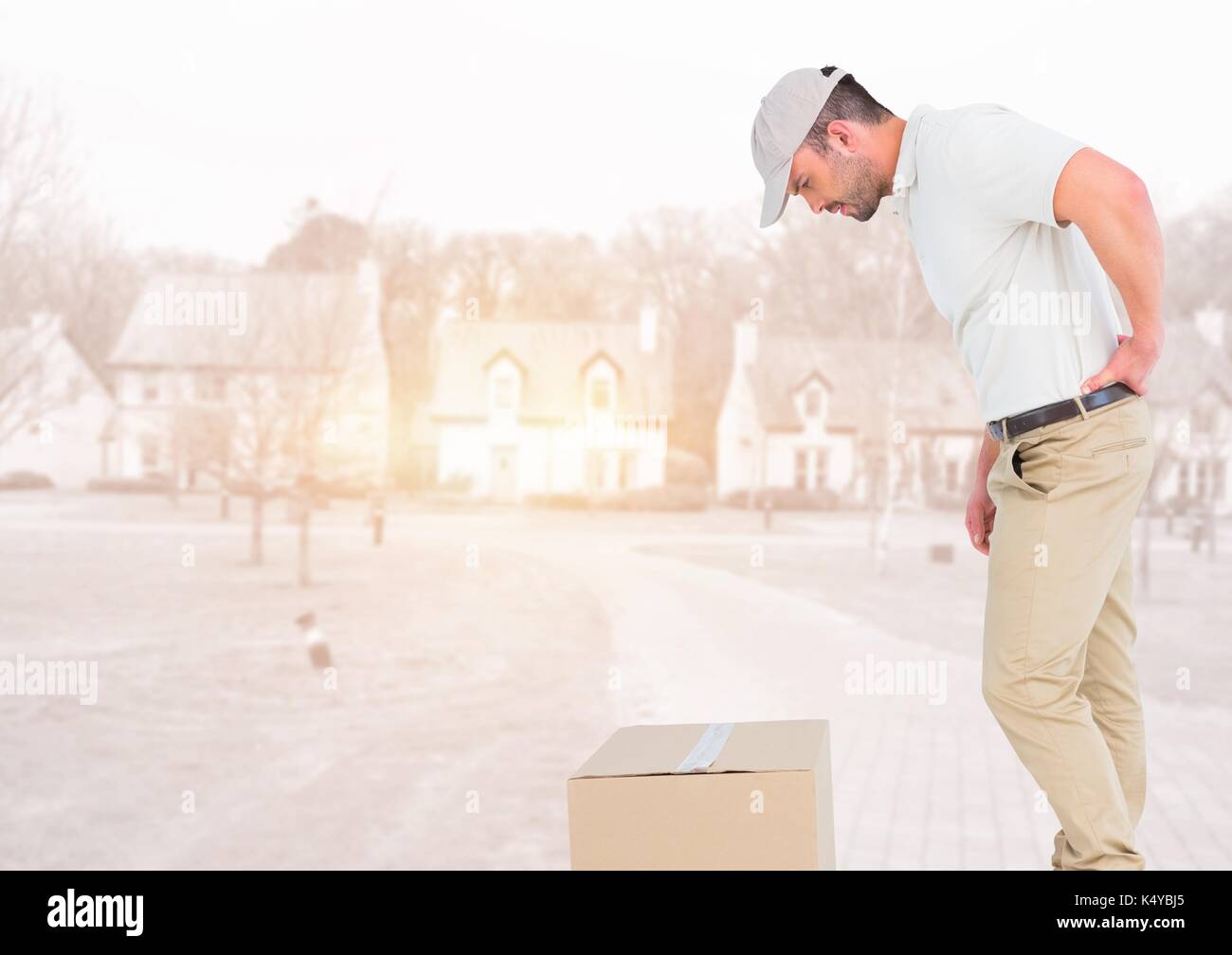 Digital composite of Delivery man looking at box against blurry housing ...